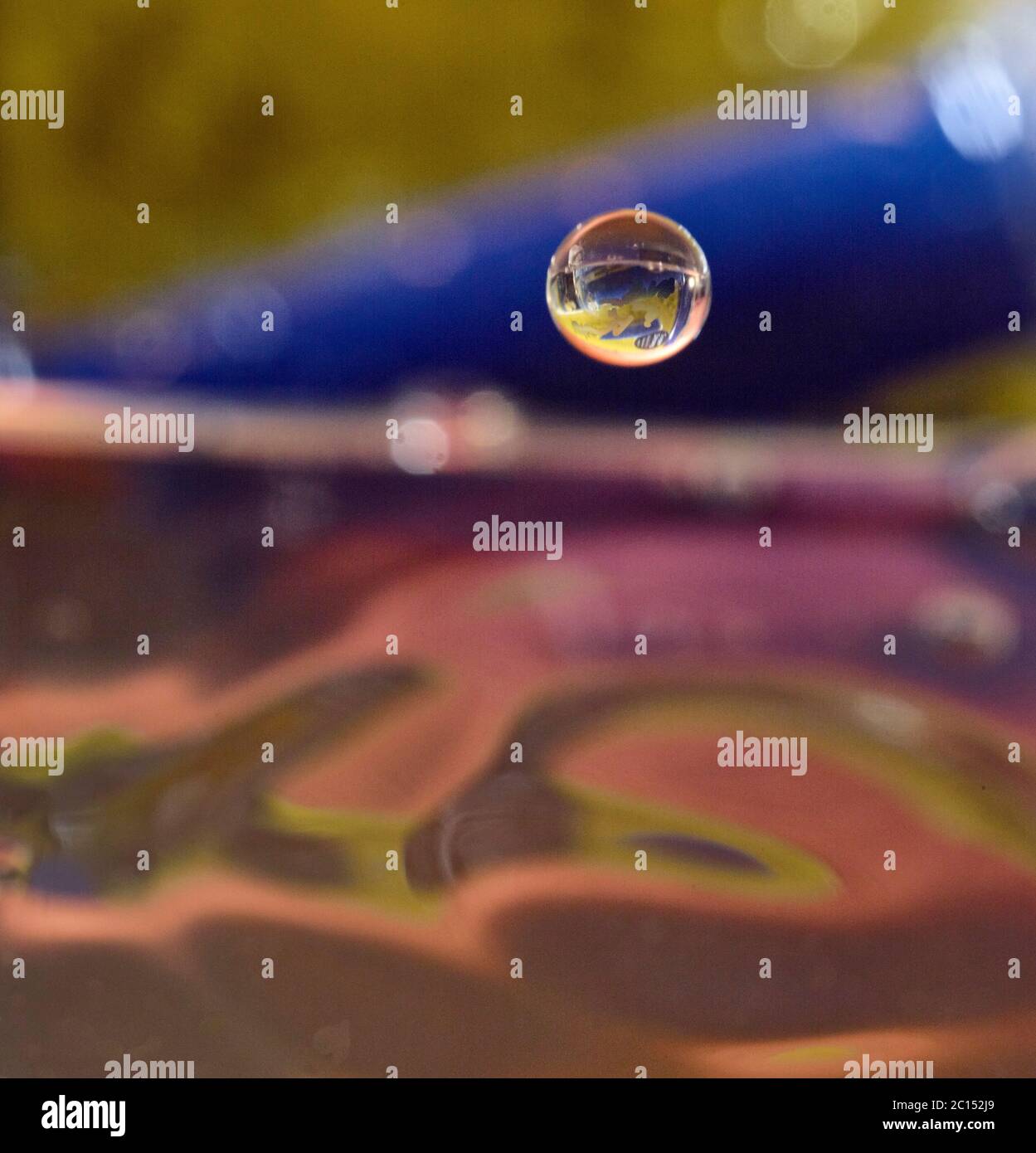 Water droplets falling on and bouncing off a pool of water, leaving ...