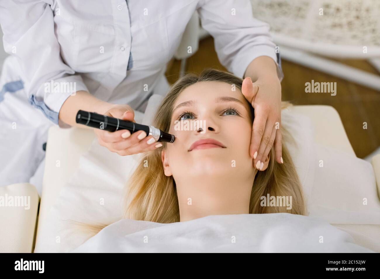 Charming young smiling Caucasian woman during face skin diagnostic in ...