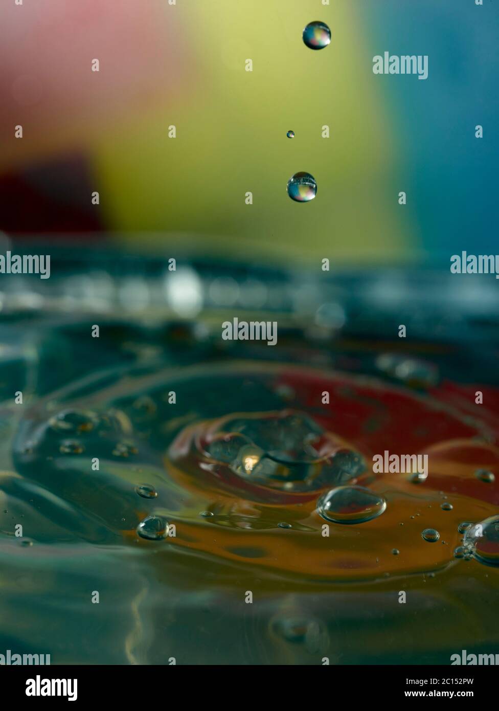 Water droplets falling on and bouncing off a pool of water, leaving ...