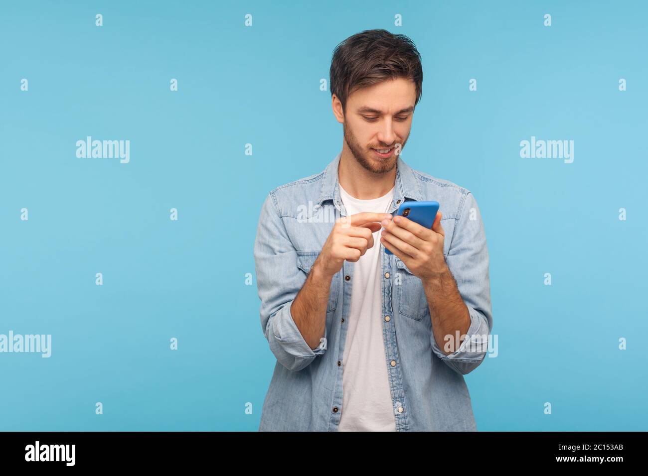 Portrait of happy smiling man in worker denim shirt texting in social ...