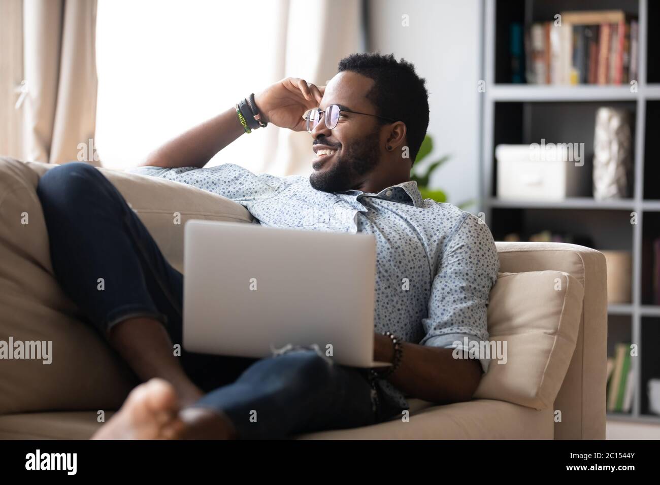 Single guy resting on couch in living room with notebook Stock Photo ...
