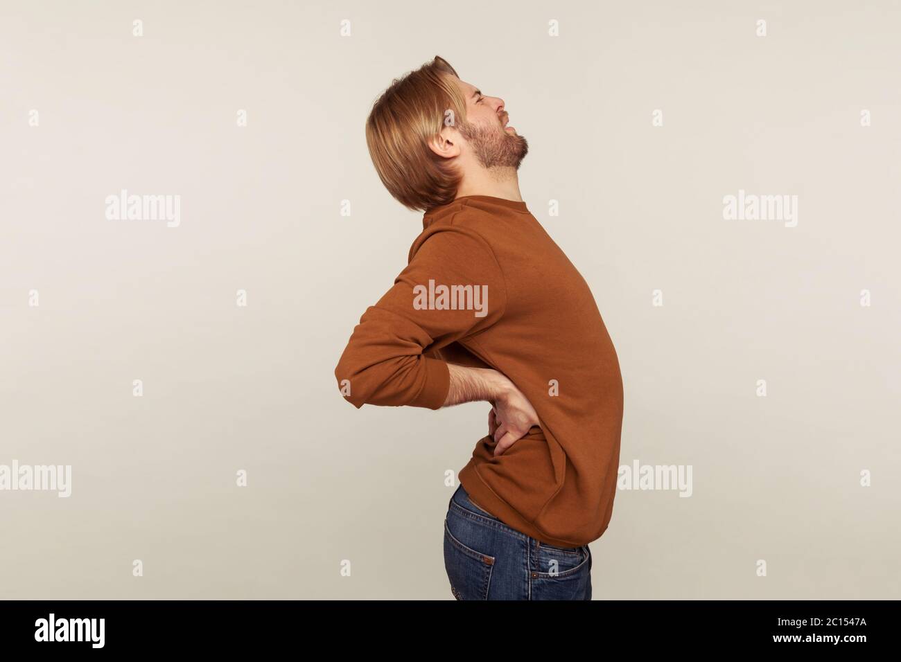 Side view of unhealthy young man suffering acute sudden pain in lower ...