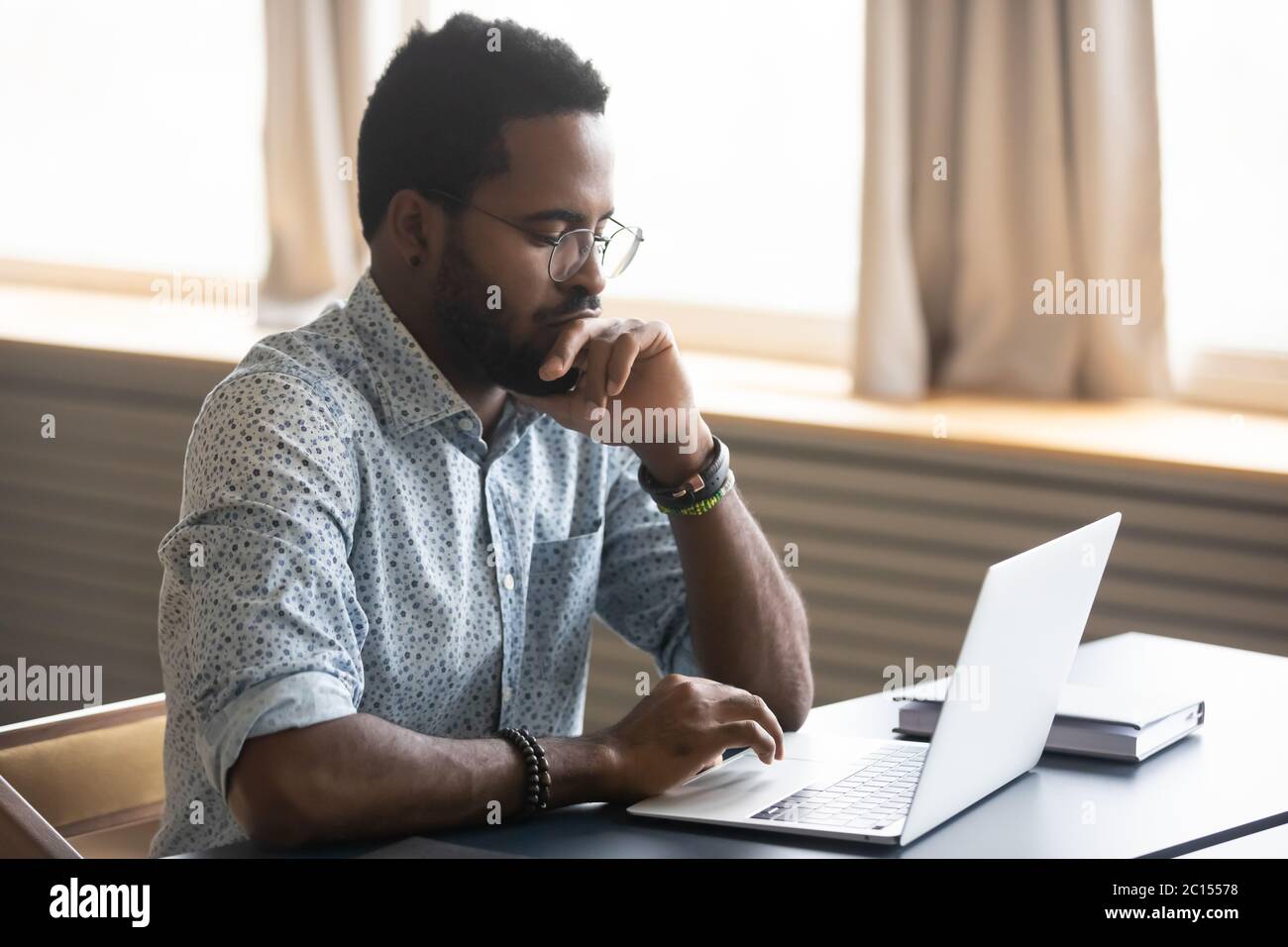 African man looking at laptop screen thinking over received email Stock ...