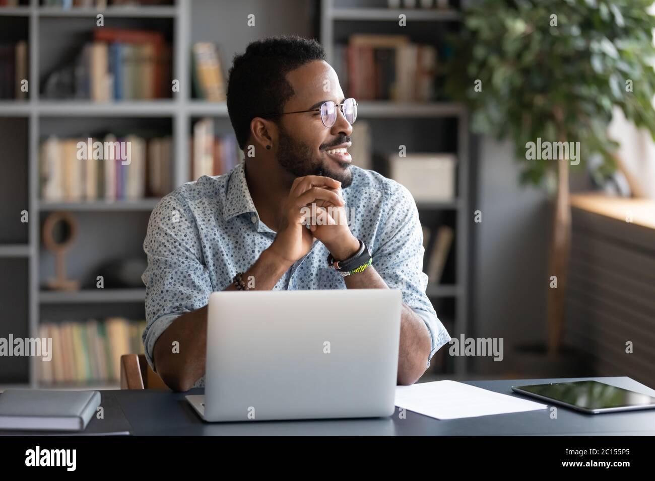 African male employee looking at window taking break from work Stock ...