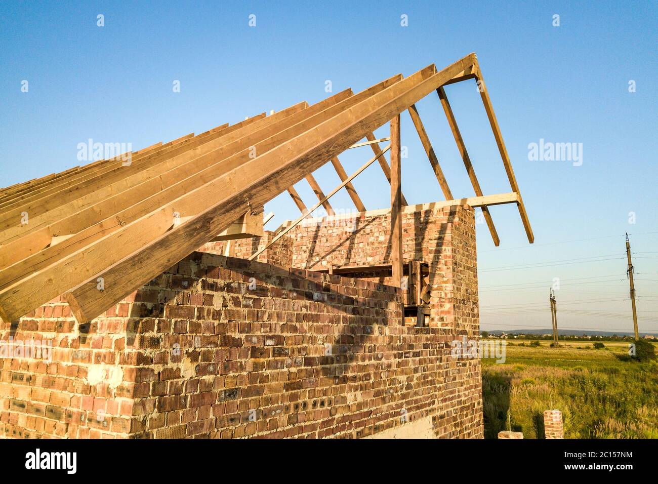 Unfinished brick house with wooden roof structure under construction ...