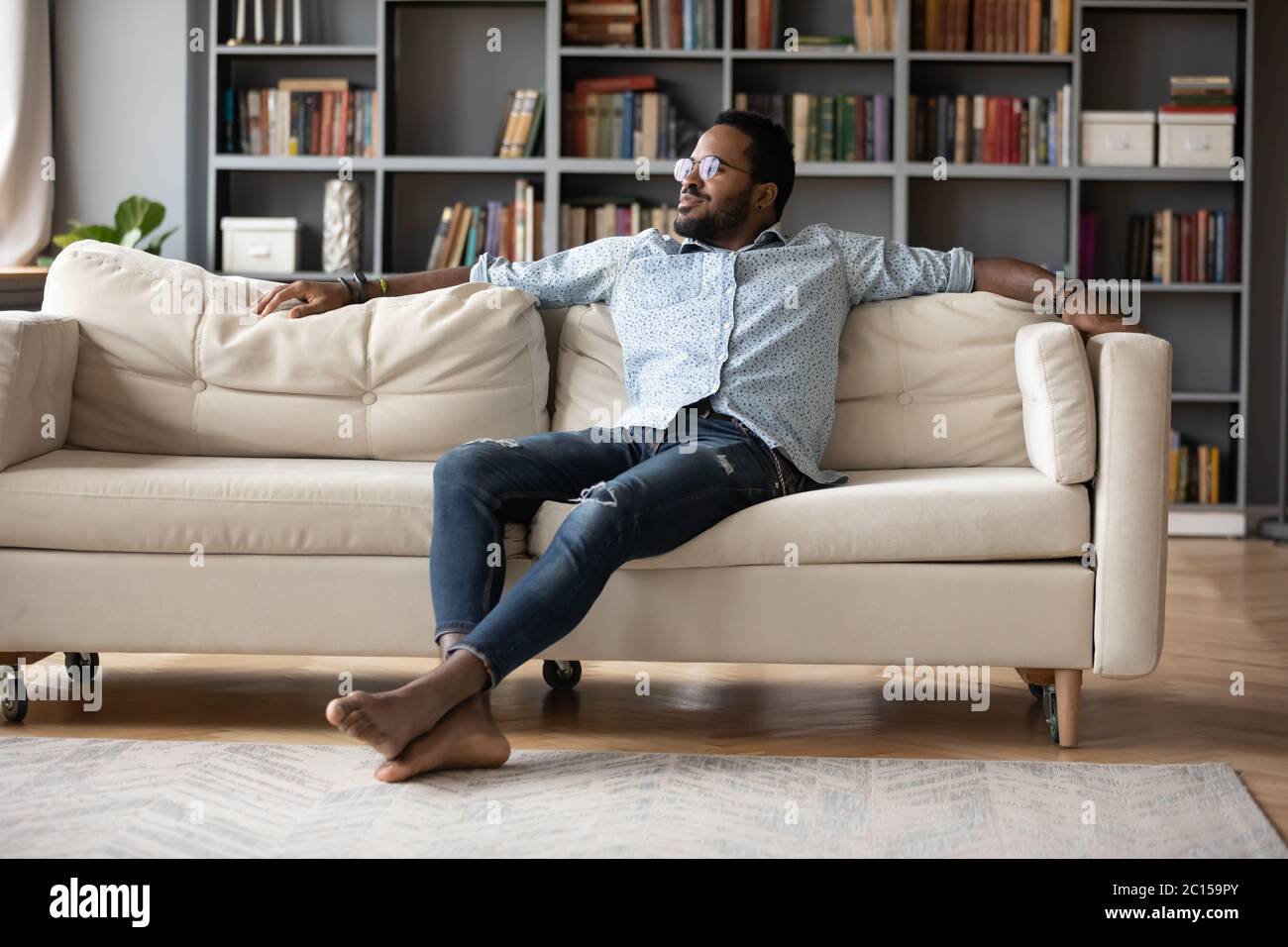 Carefree african man resting on sofa in cozy living room Stock Photo ...