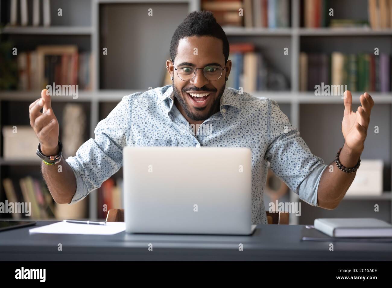 African guy looking at pc screen feels shocked Stock Photo - Alamy