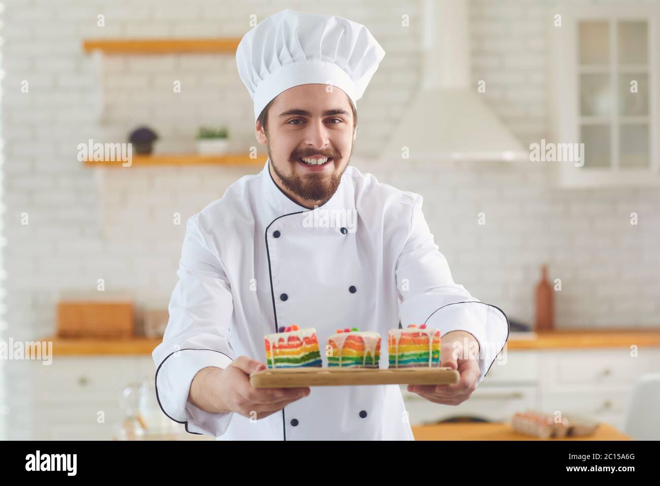 Confectioner man smiles while standing with cake in his hands at the ...