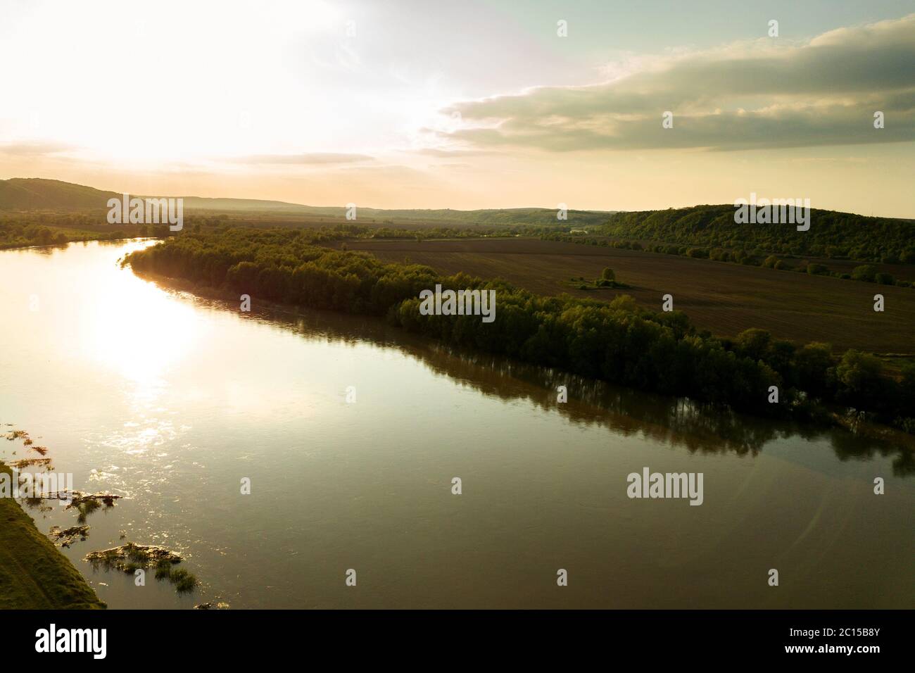 Aerial view of bright river flowing through green meadows in spring ...