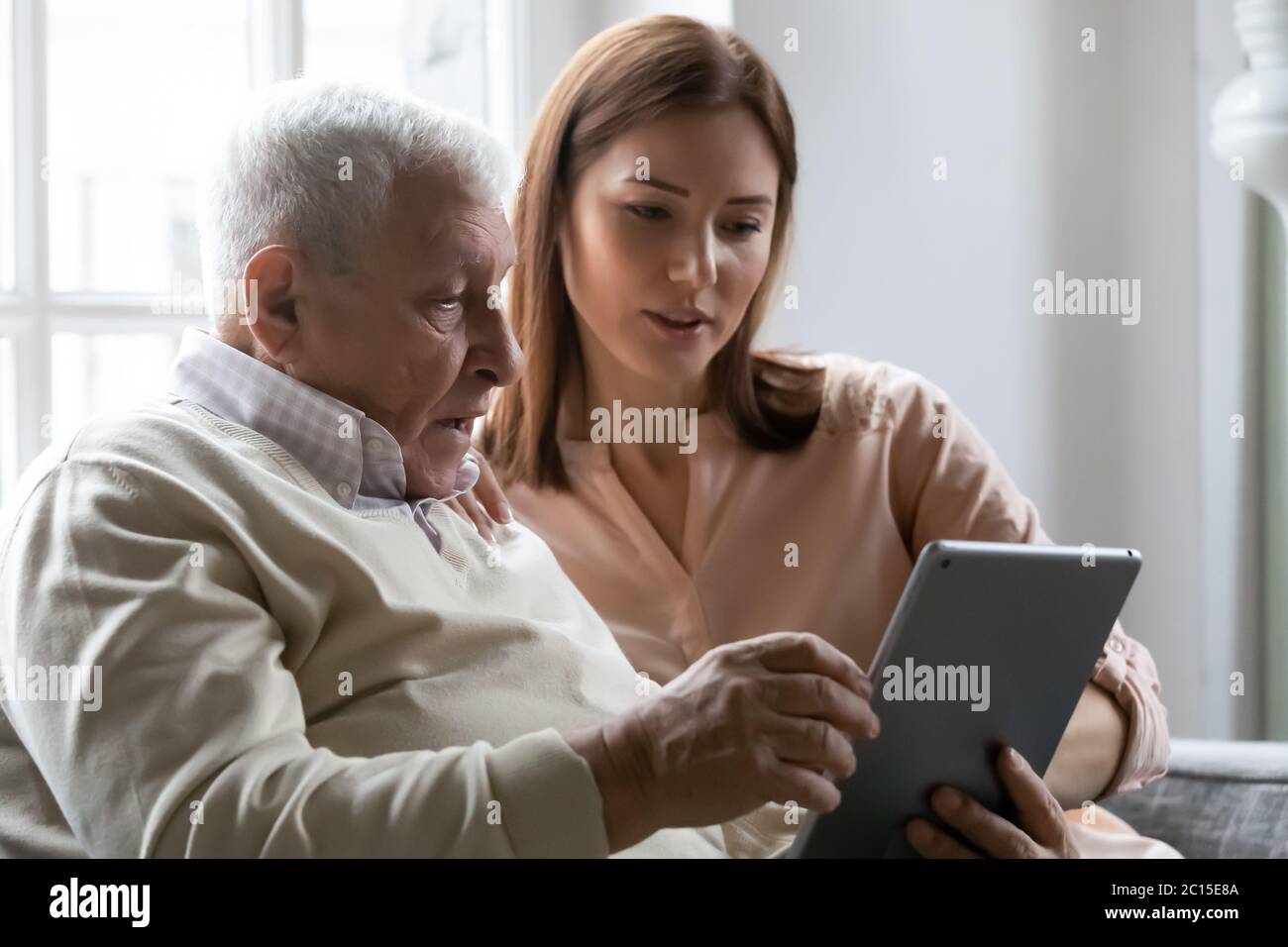 Caring grownup daughter teaching elderly father to use tablet Stock ...