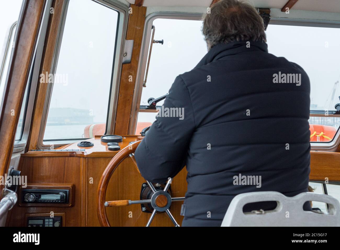Captain driving an old wooden boat - rear view Stock Photo - Alamy