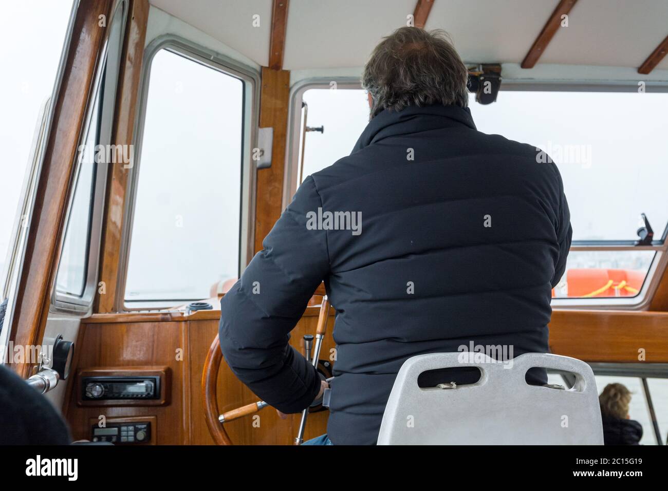 Captain driving an old wooden boat - rear view Stock Photo - Alamy