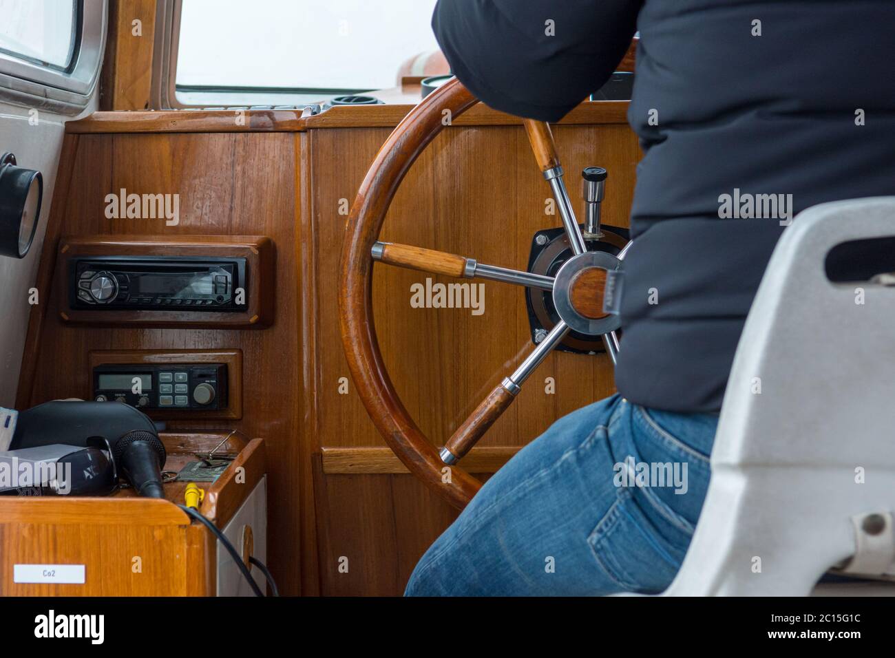 Captain driving an old wooden boat - rear view Stock Photo - Alamy