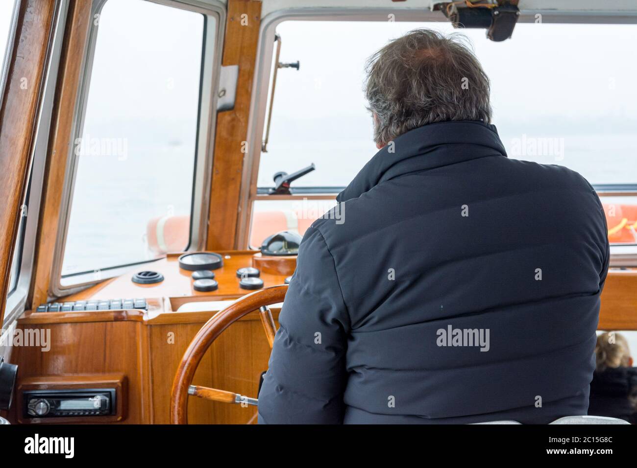 Captain driving an old wooden boat - rear view Stock Photo - Alamy