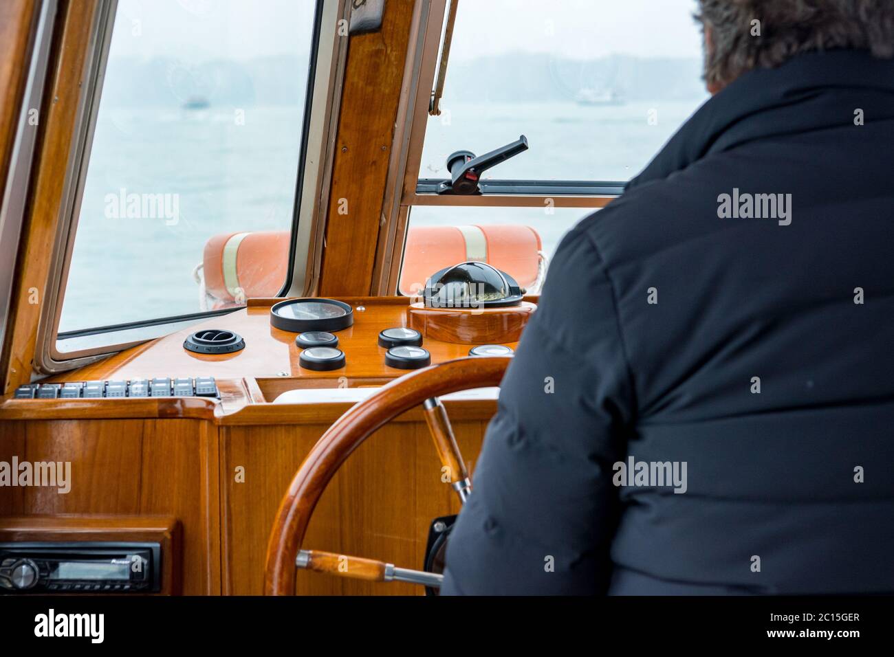 Captain driving an old wooden boat - rear view Stock Photo - Alamy