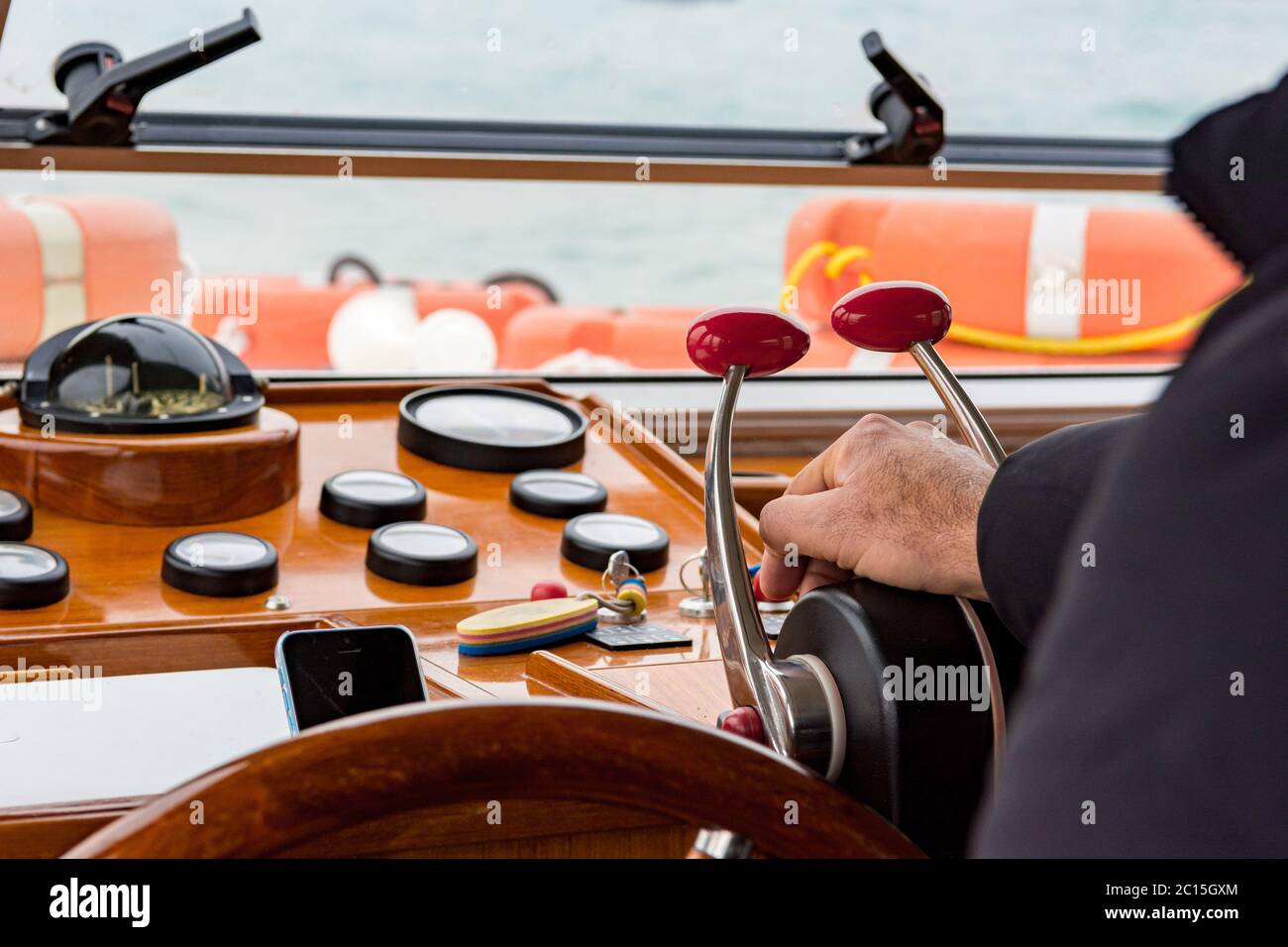 Captain driving an old wooden boat - rear view Stock Photo - Alamy