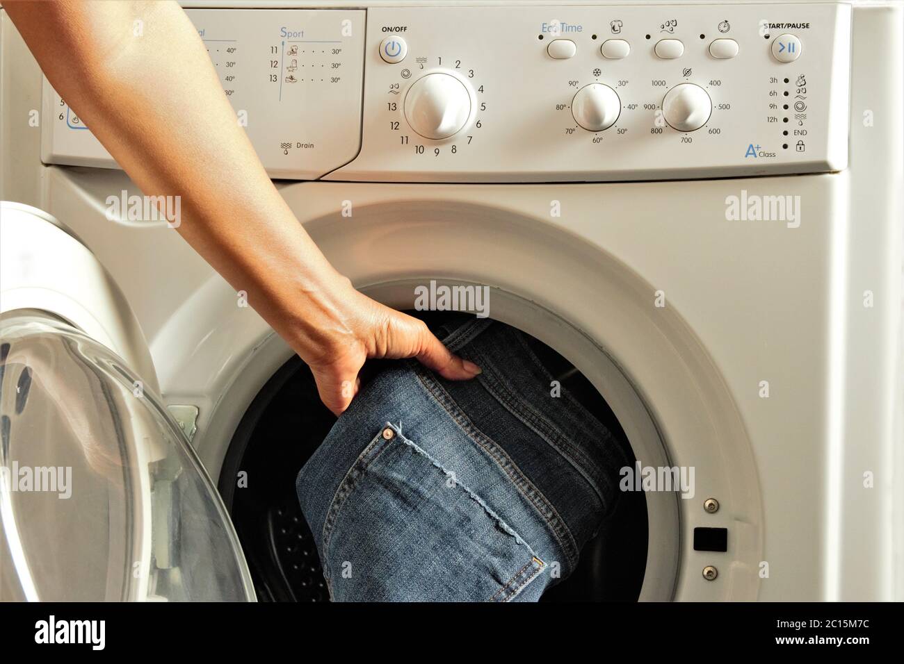 Woman hand taking blue jeans from washing machine Stock Photo - Alamy