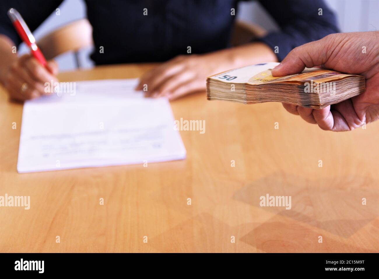 Hand giving a lot bank notes to woman is working on her desks Stock ...