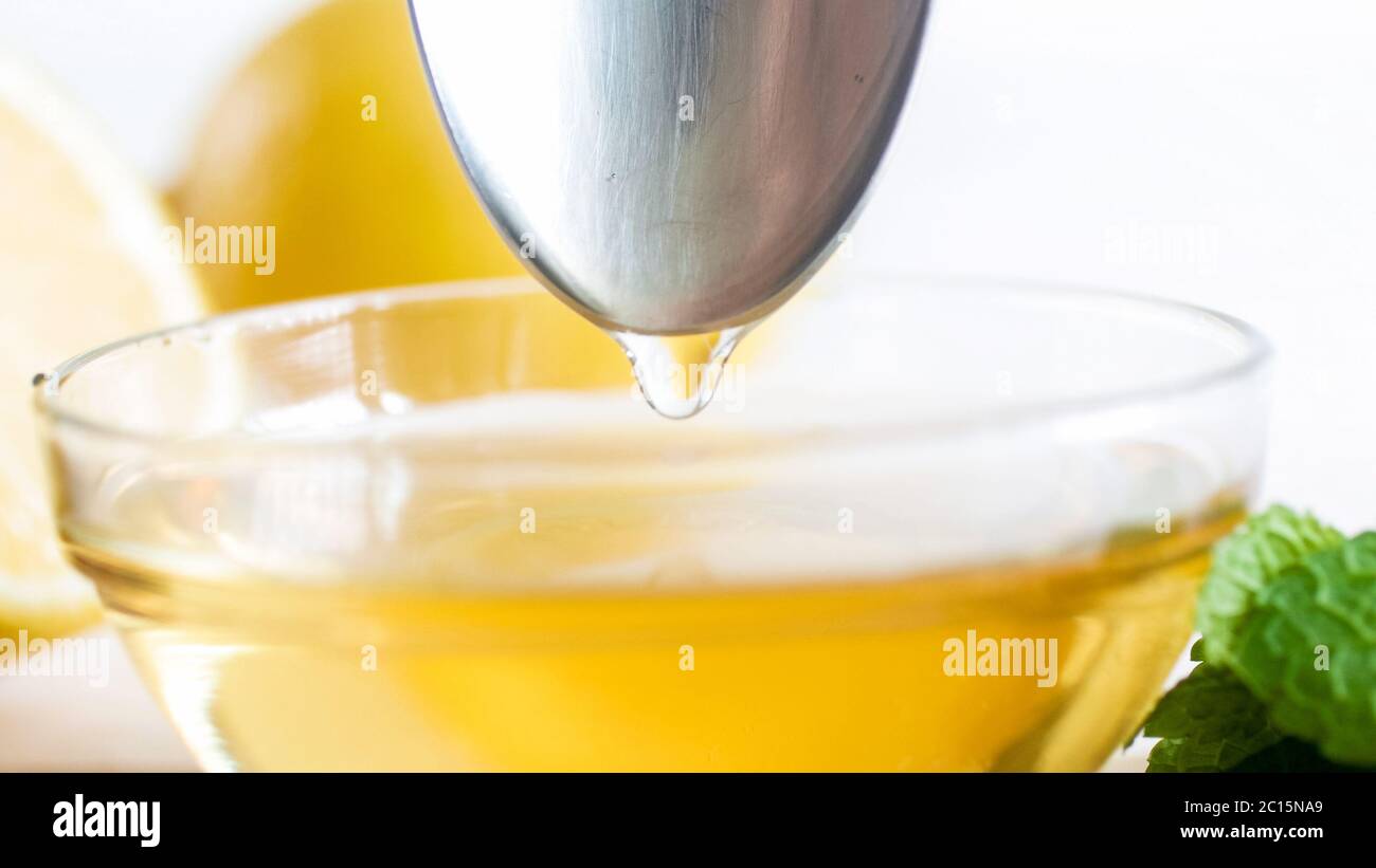 Closeup image of honey dropelts falling from metal spoon in honey jar ...