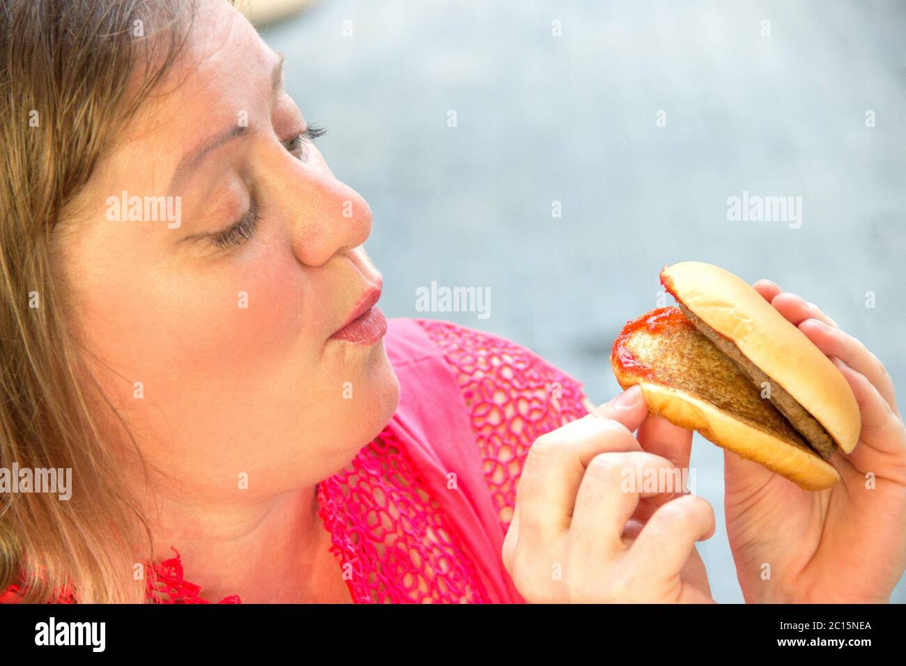 Thick woman in red clothes eating fast food hamburger and french fries ...
