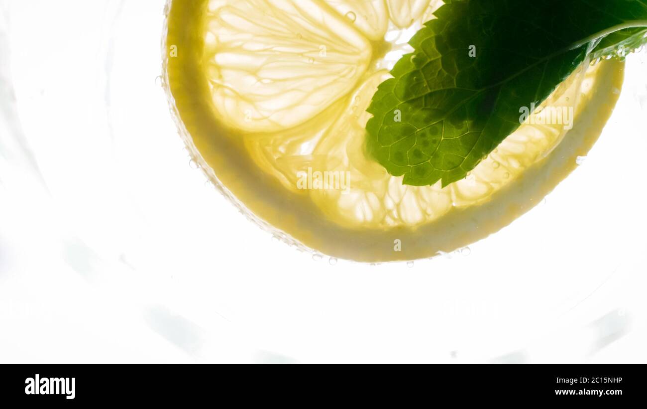 Macro photo of lemon slice and mint leaf floating in cold lemonade ...