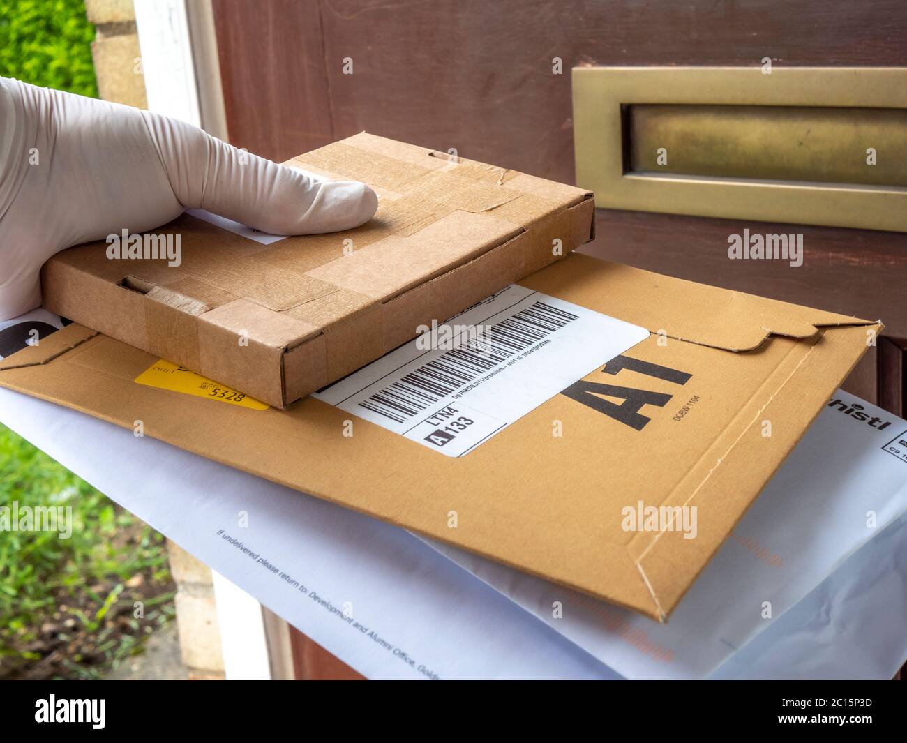 Postman wearing a protective rubber glove delivering mail items to an ...