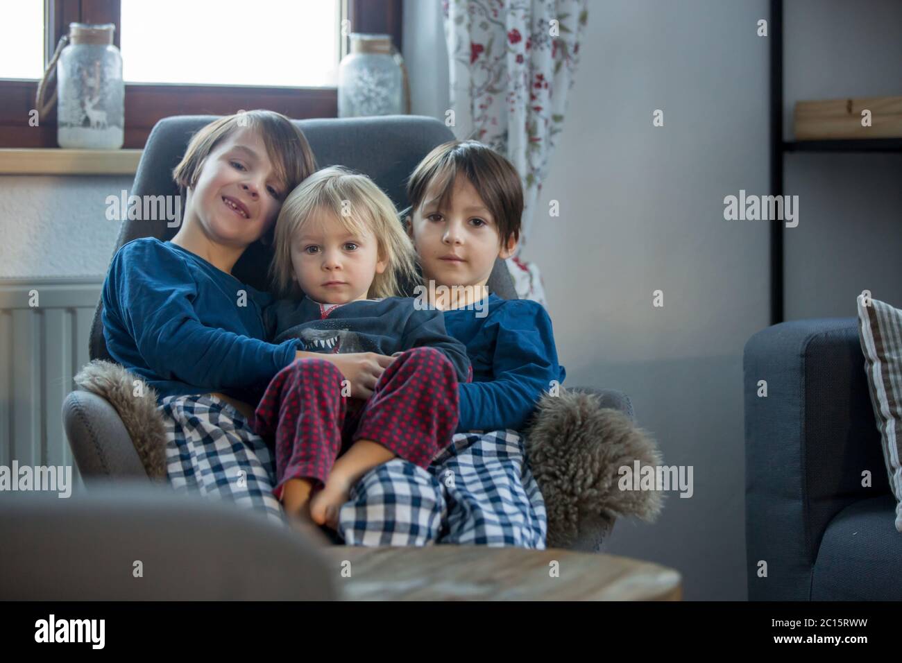 Preschool boys and toddler, sitting in rocking chair, hugging Stock ...