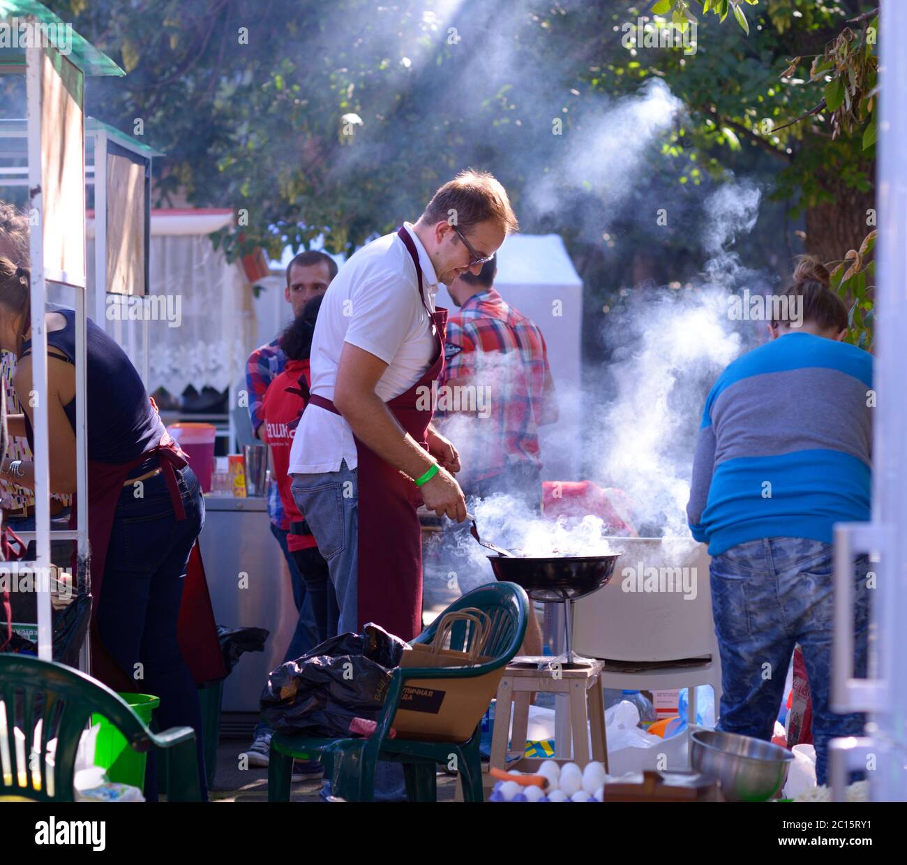 Male cook preparing meal on open fire at the outdoor kitchen set behind ...