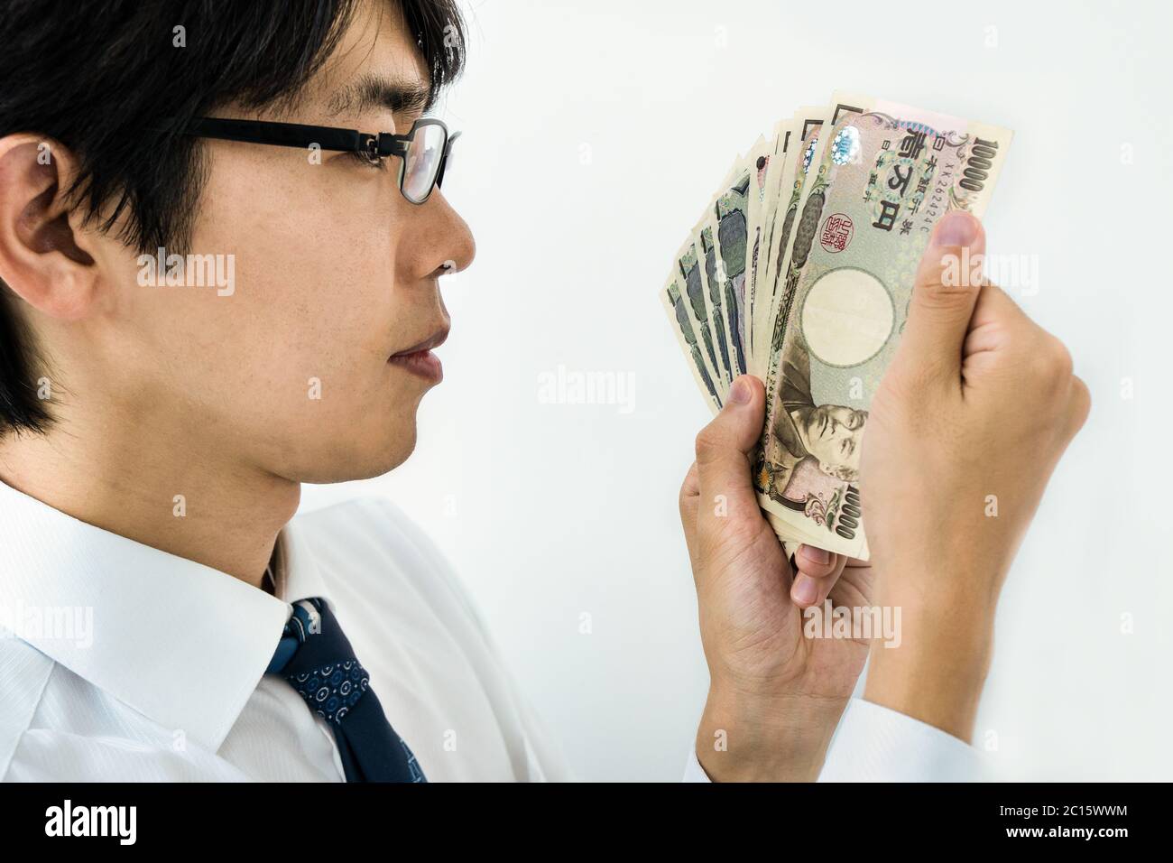 Young Japanese businessman counting money. Holding a stack of japanese ...