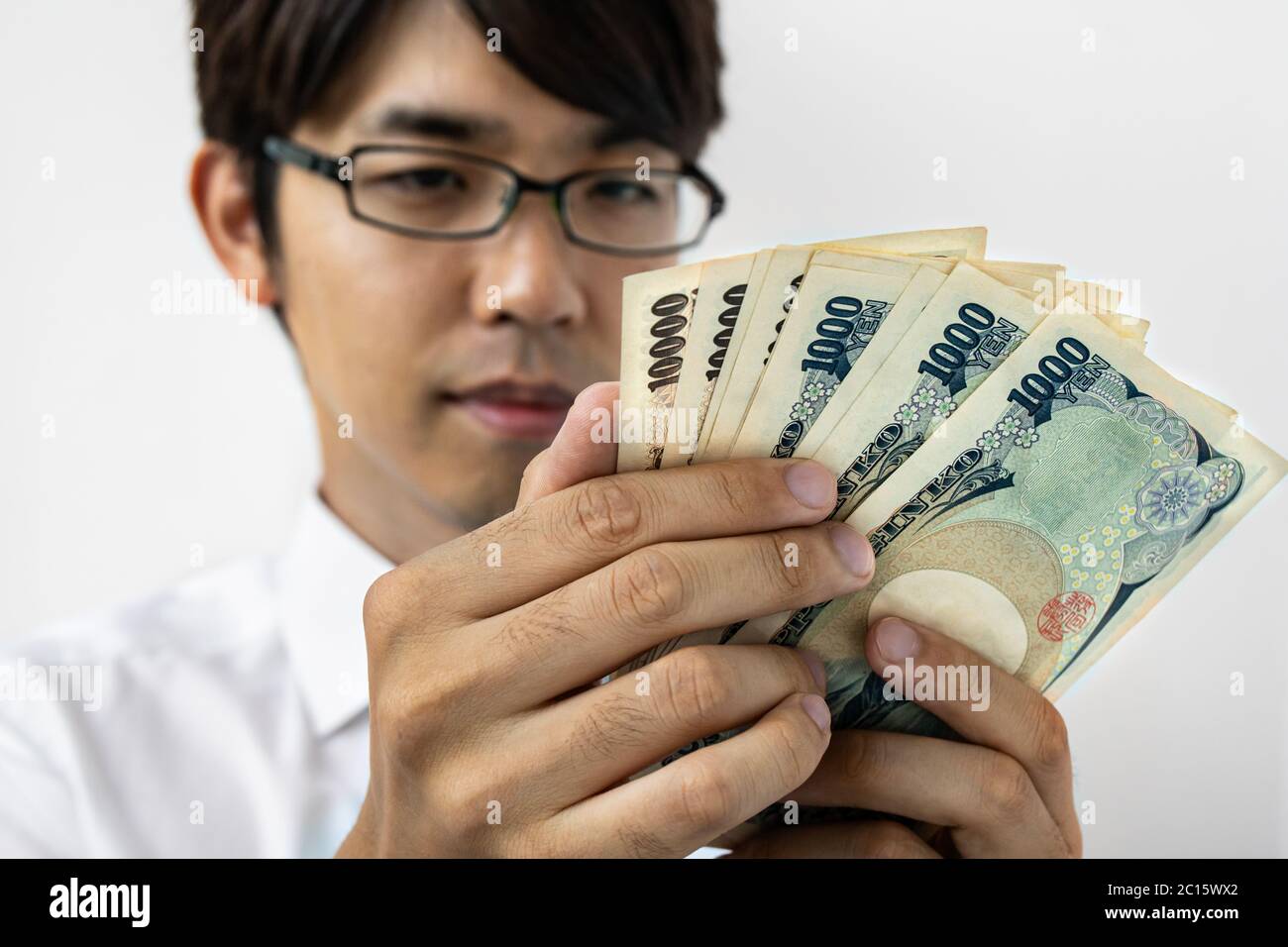 Young Japanese businessman counting money. Holding a stack of japanese ...