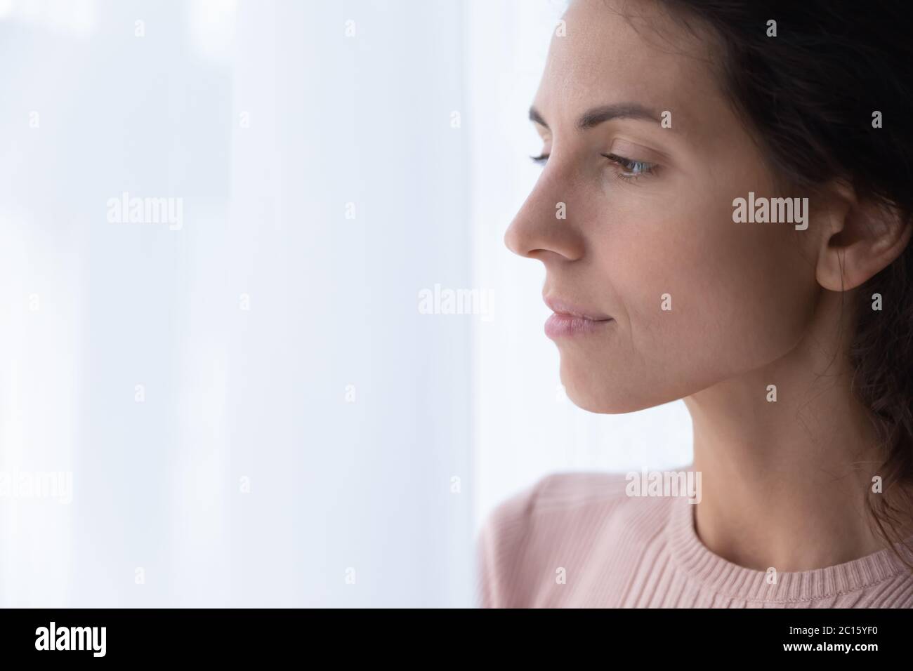 Close up thoughtful young woman looking through window Stock Photo - Alamy