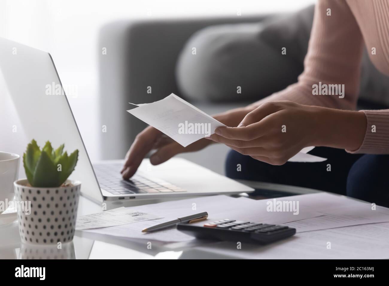 Close up woman holding receipt, using laptop, calculating bills Stock ...