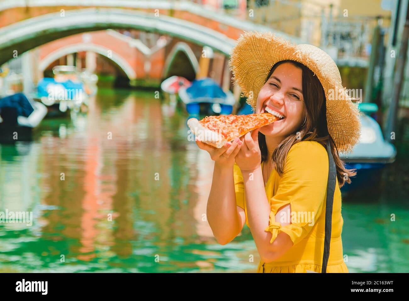 woman sitting on pond with view of venice canal eating pizza Stock ...