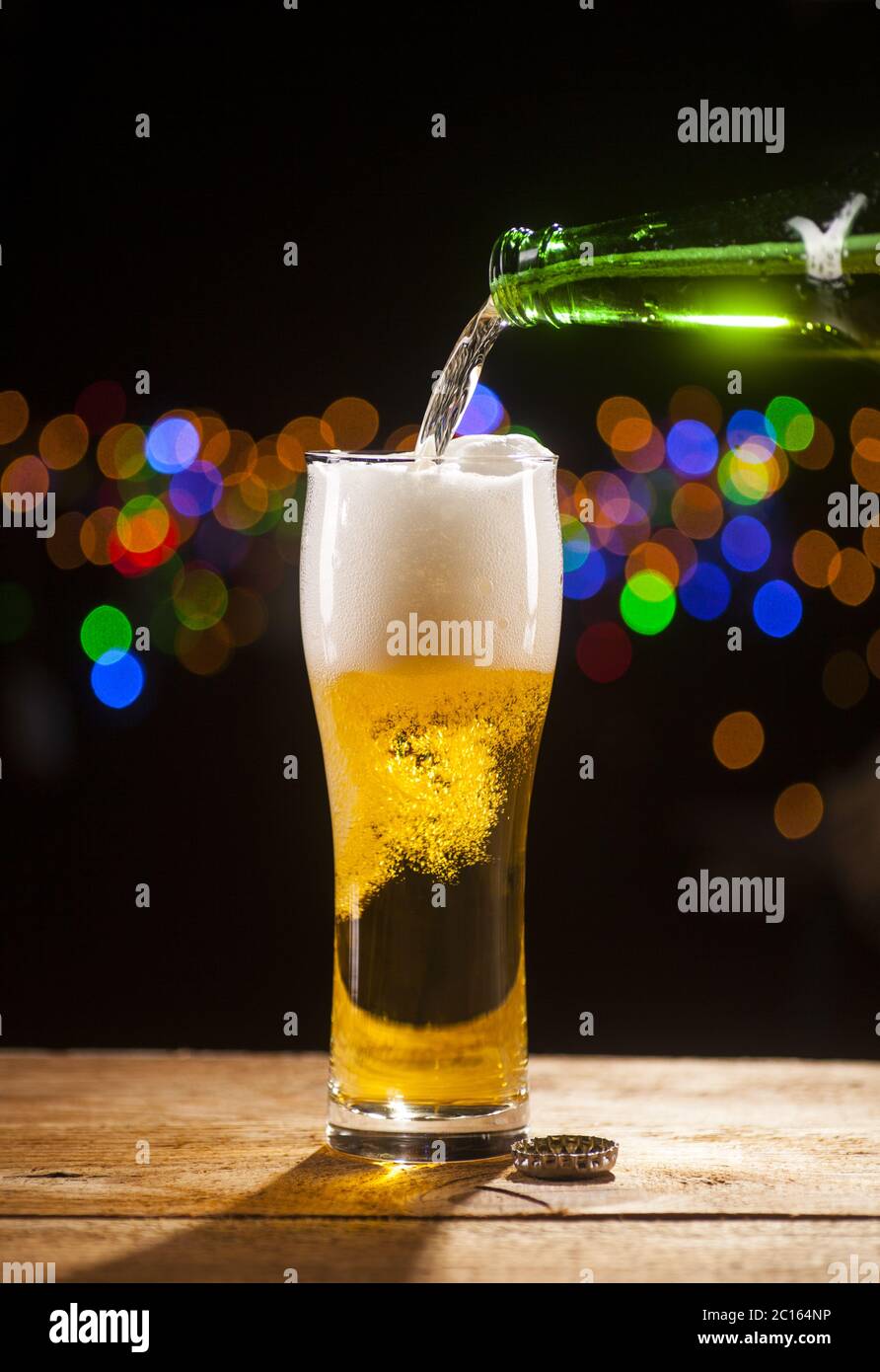 Beer is pouring into glass on bar lights background Stock Photo - Alamy