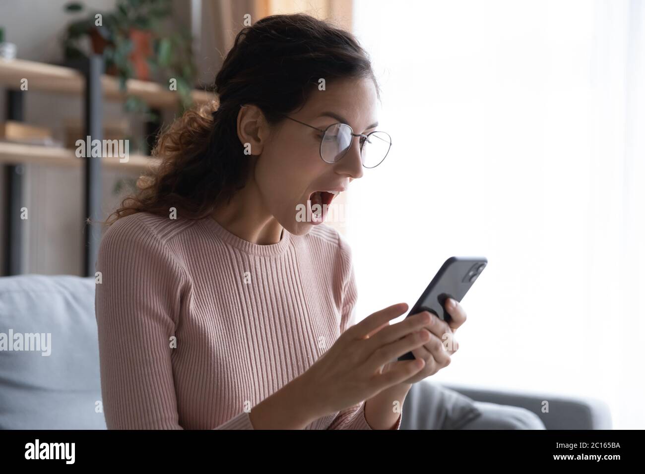 Overjoyed woman with open mouth looking at smartphone screen Stock ...
