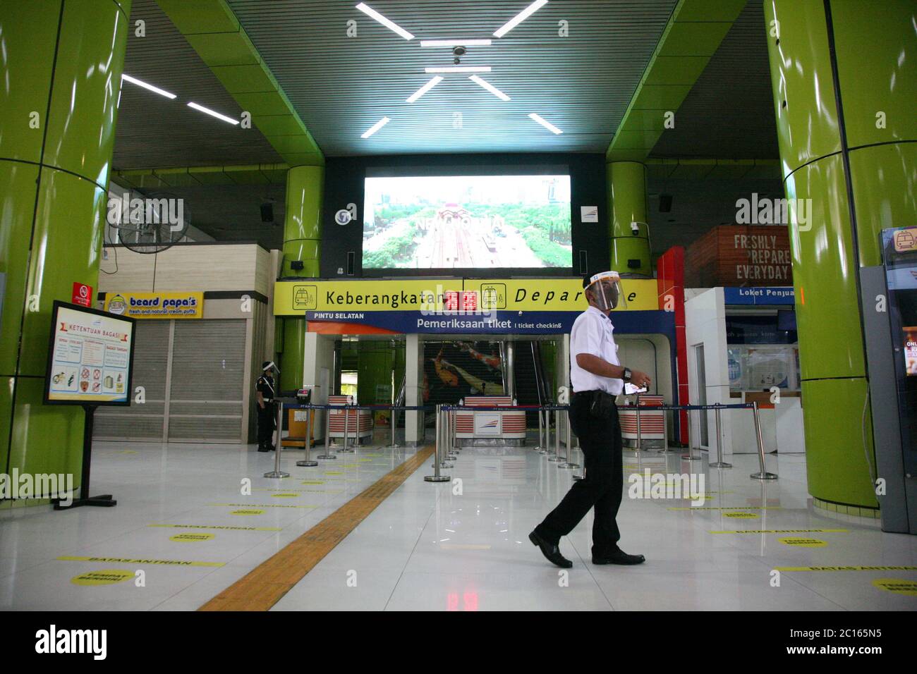 Officers wearing face masks guarding the entrance of the arrival of passengers at Gambir Station ...