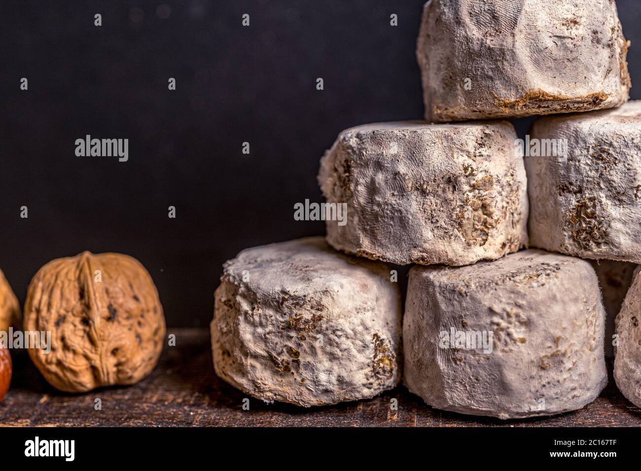 French cheese Crottin de Chavignol with hazelnut in the dark background ...