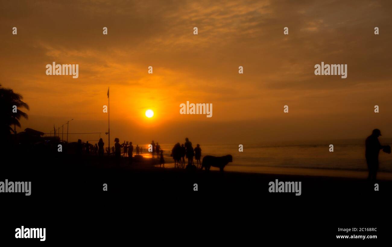 Black silhouette of people walking on Tonsupa beach on a cloudy sunset ...