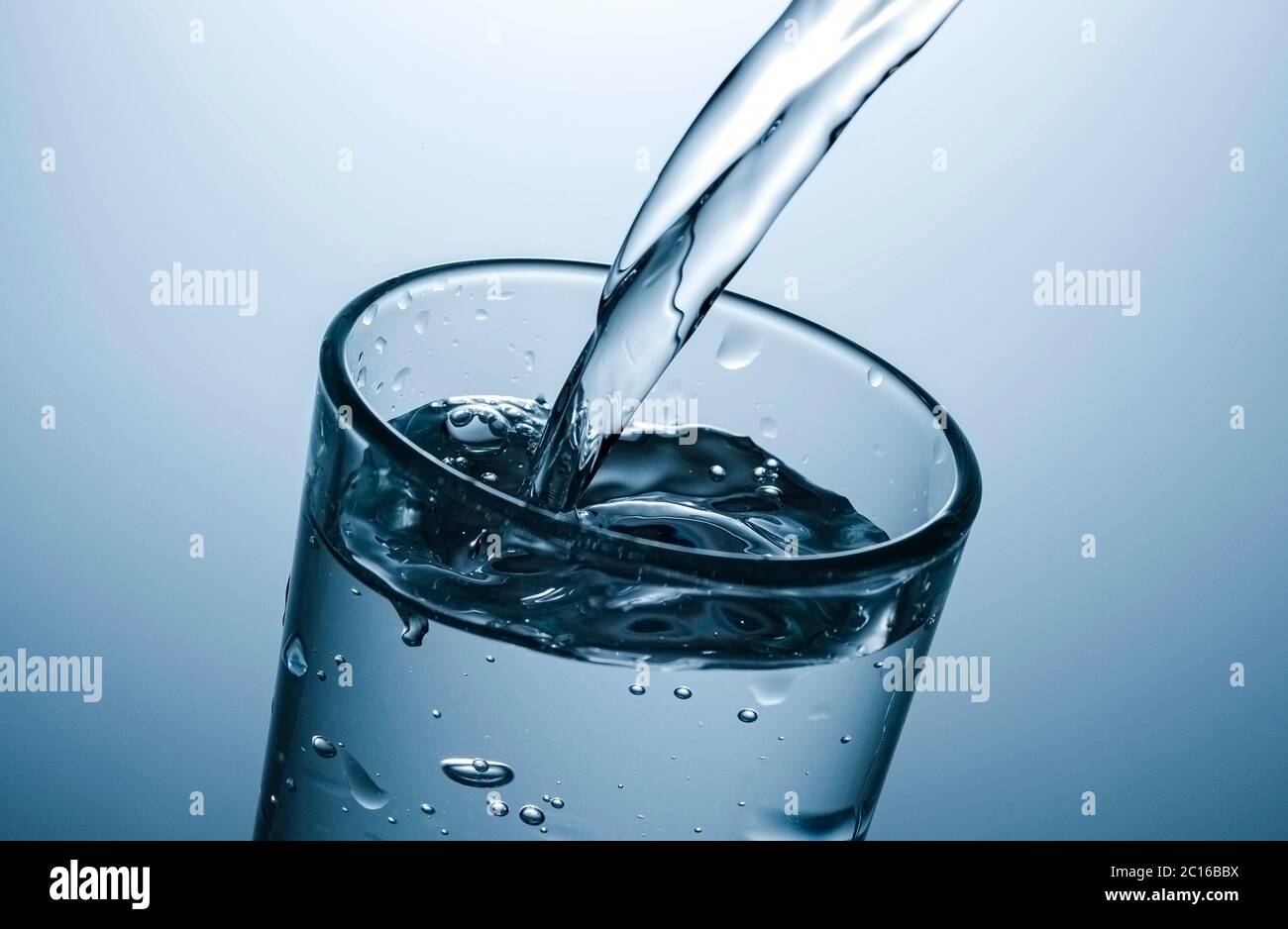 Pouring sparkling water into a glass in close up on the rim of the almost full glass with ...