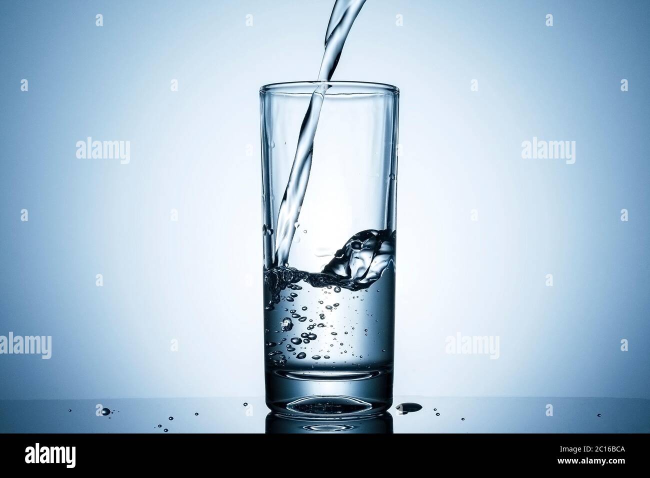 Pouring sparkling water into a glass in close up on the rim of the with effervescent bubbles ...