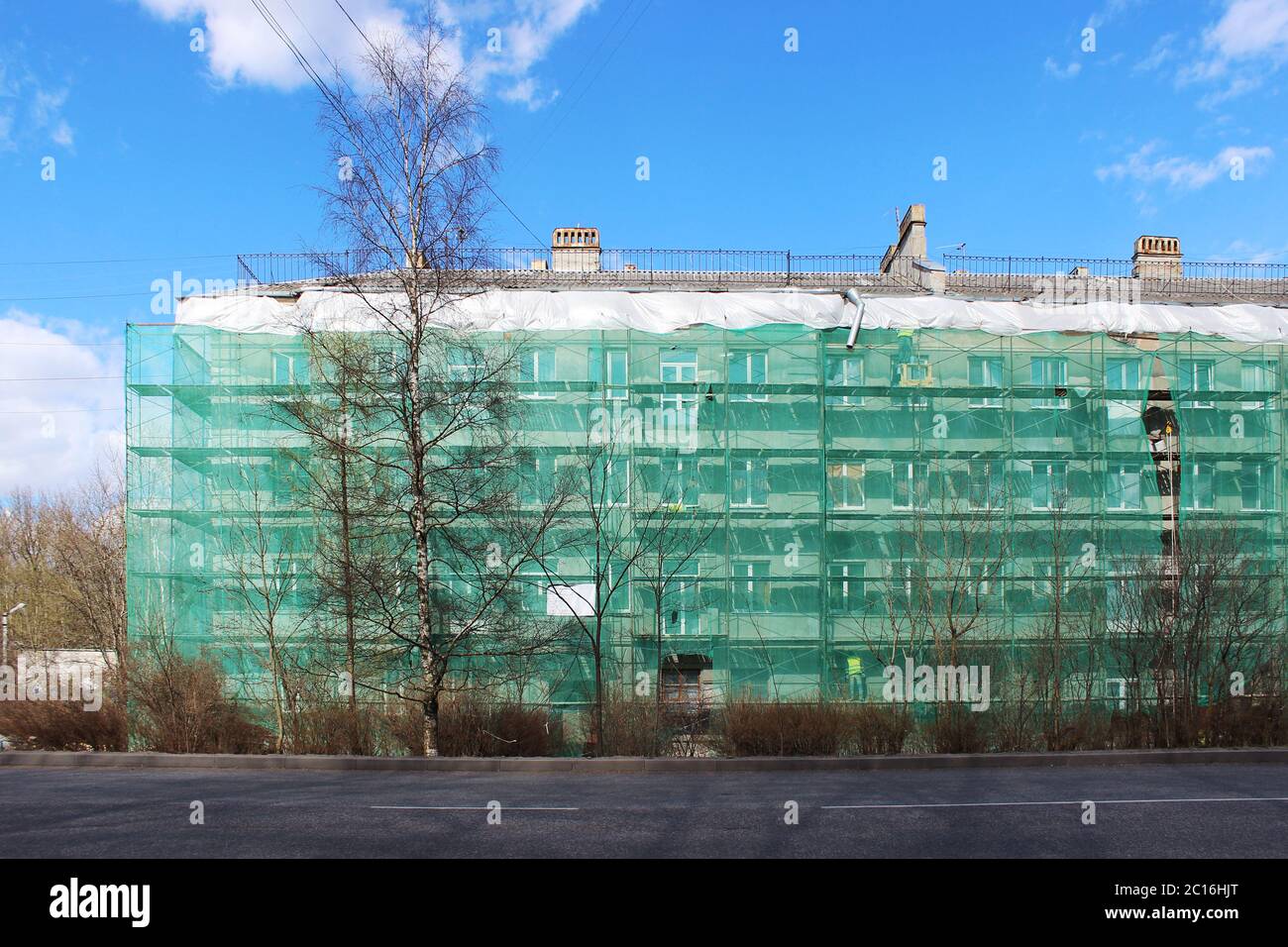 The residential building, covered with building scaffolding and green ...