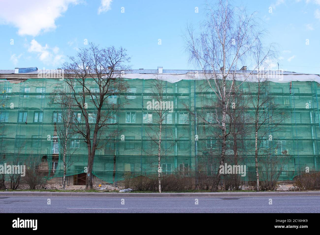 The residential building, covered with building scaffolding and green ...