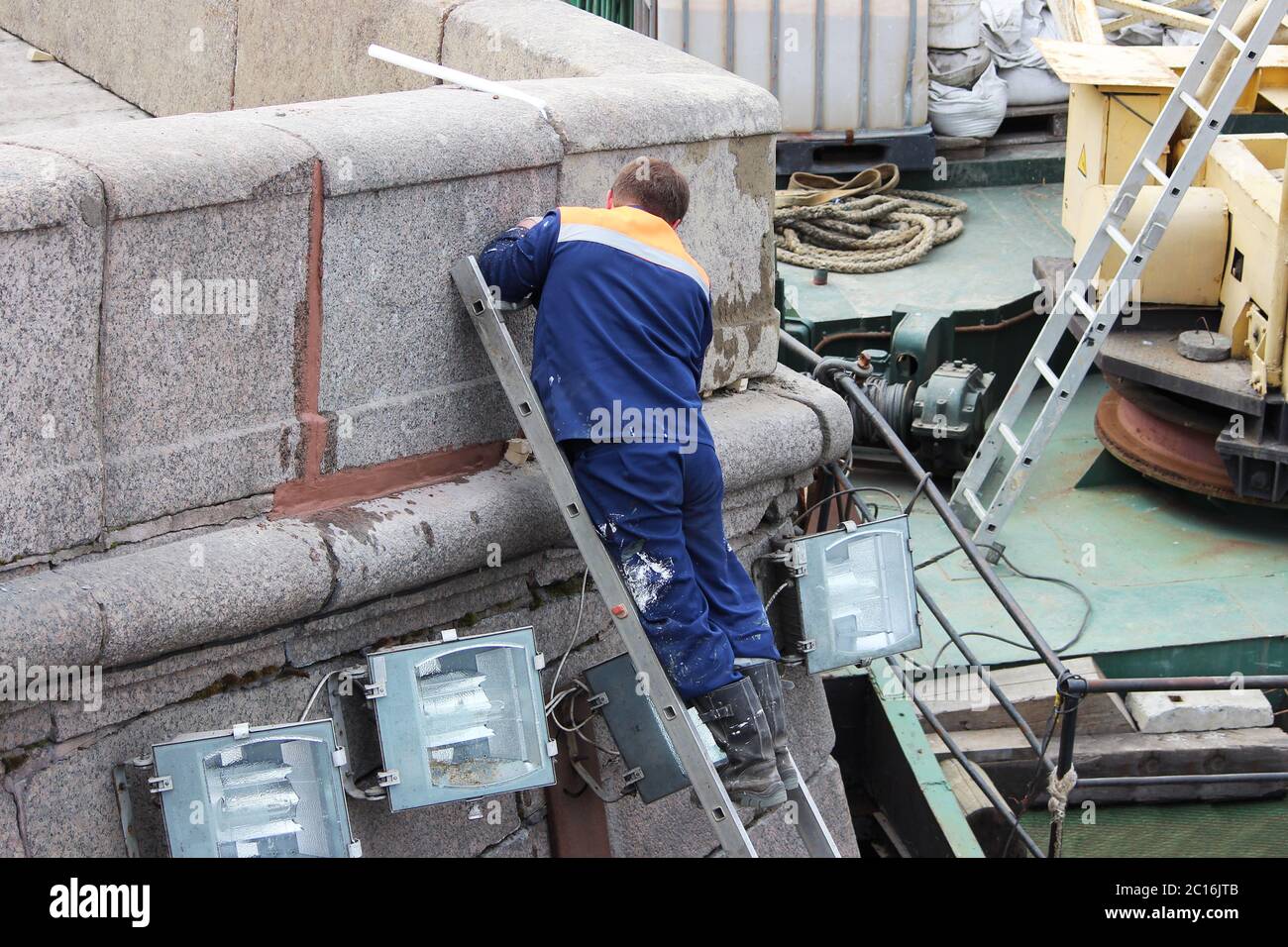 The worker mason repairs the seams between the granite slabs on the ...