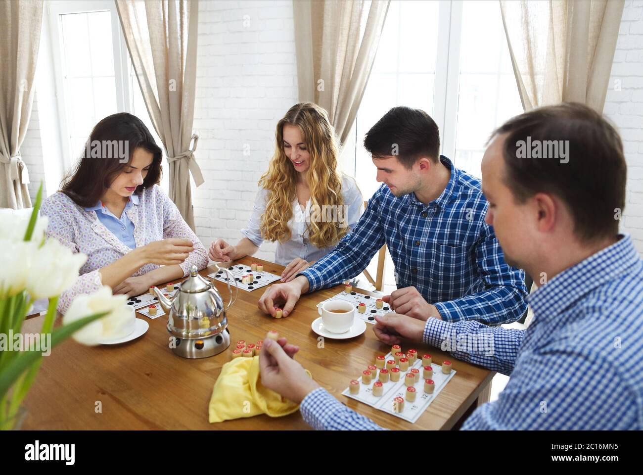 Happy young friends playing board game together Stock Photo - Alamy