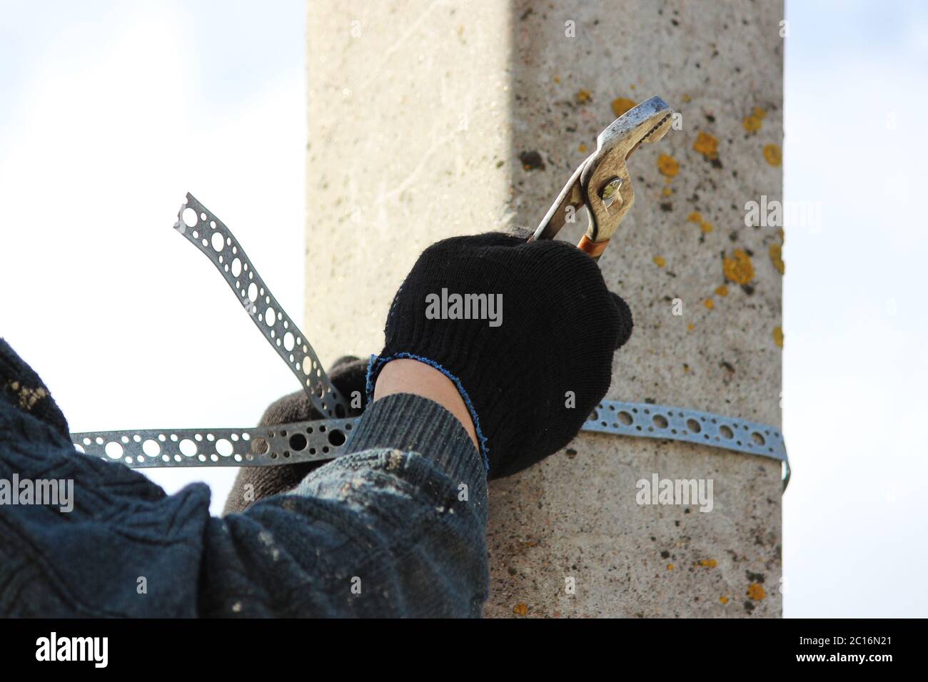 Worker affixes a chrome clamp to a post for hanging a road sign Stock ...