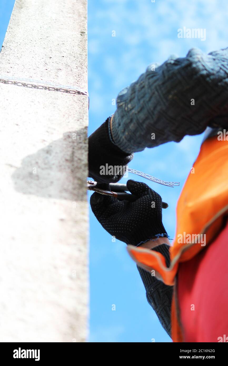 Worker affixes a chrome clamp to a post for hanging a road sign Stock ...