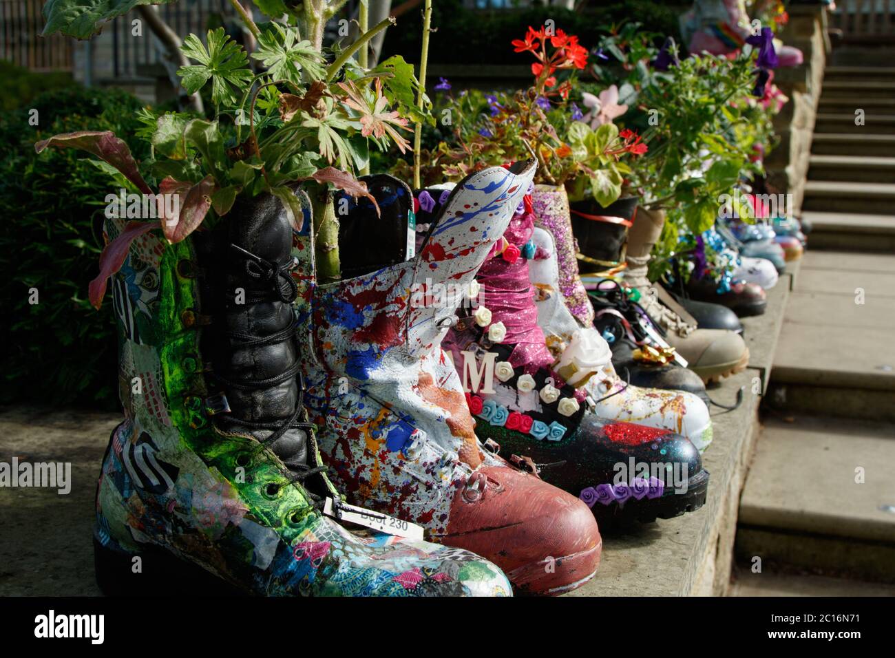 Row of multi-coloured leather painted boots with flowers growing in ...