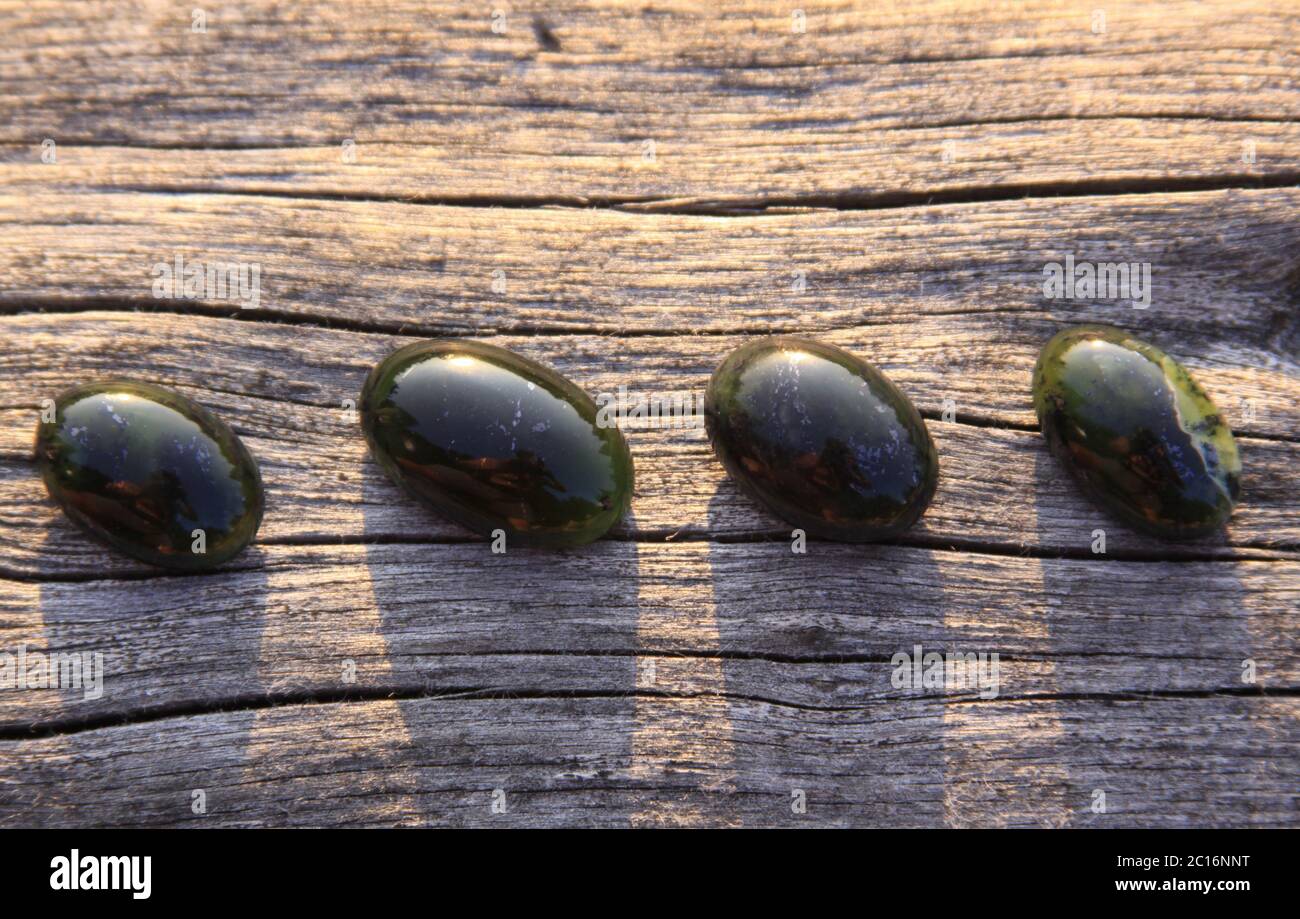 Black jade translucent green stone in sunlight on wood. The black jade ...