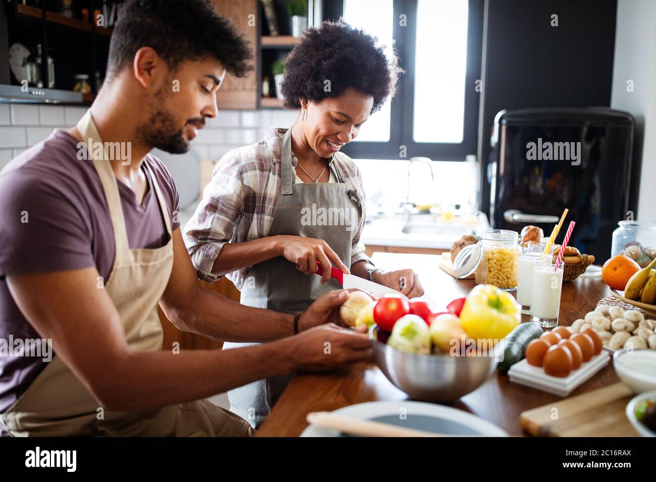 Beautiful young couple having fun and laughing while cooking in kitchen ...