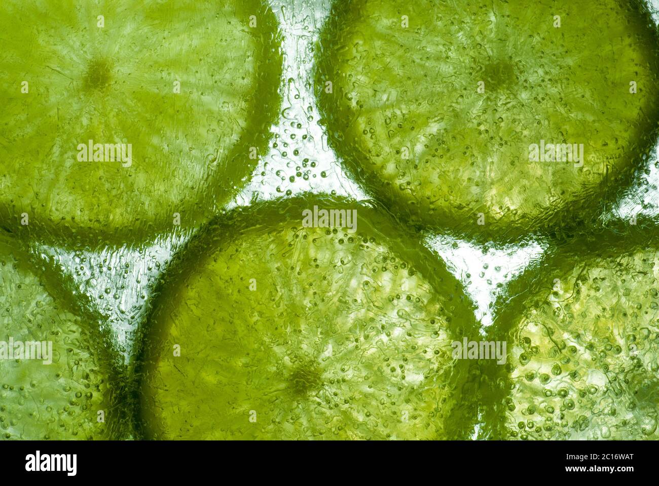 fresh lime slices frozen in translucent ice with back lit abstract ...